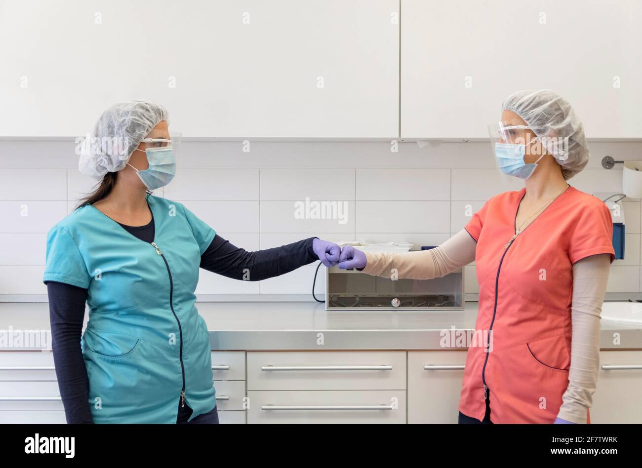 Two nurses wearing protective masks, fist bump, medical workers, social ...