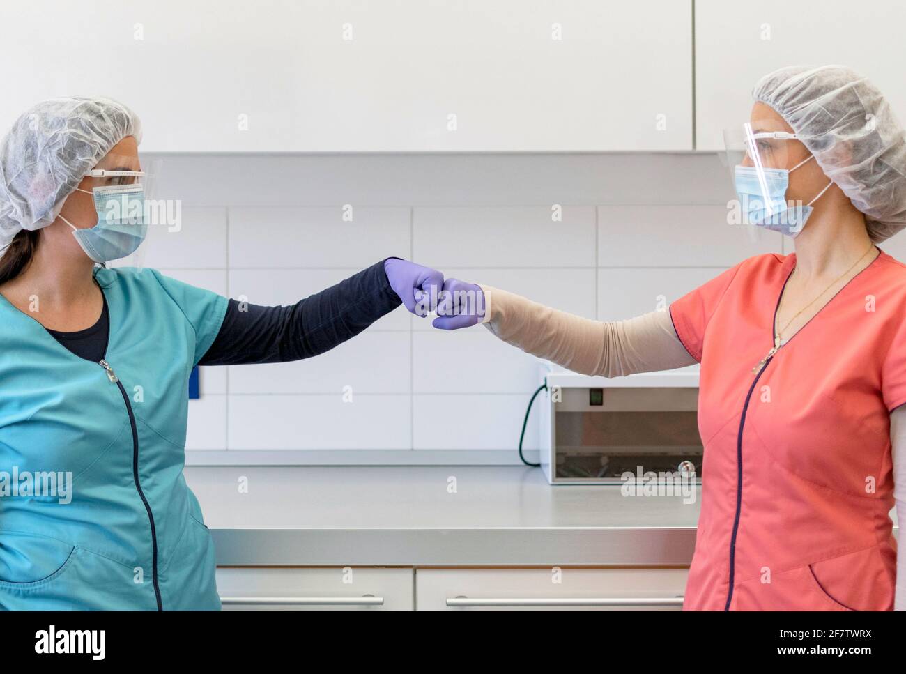 Two nurses wearing protective masks, fist bump, medical workers, social ...