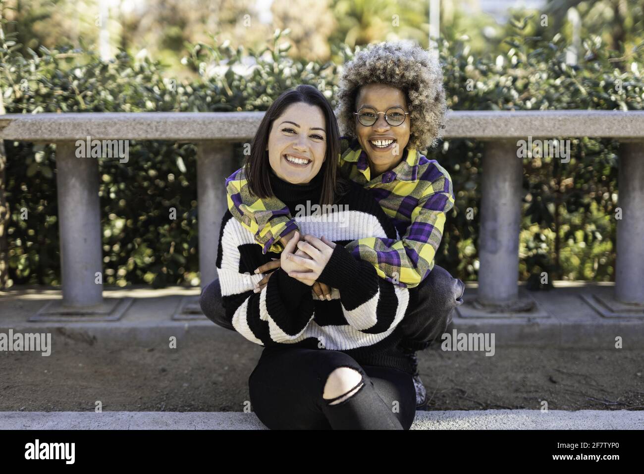 Happy African-American and Caucasian female friends hugging each other ...