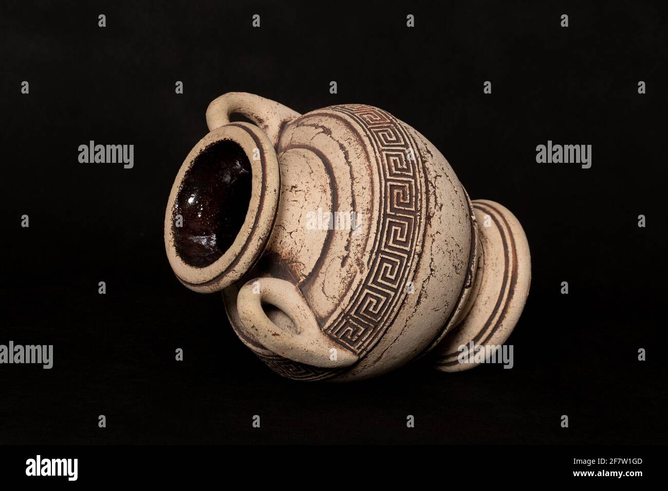 Clay light amphora lies on its side on a black background in a room in ...