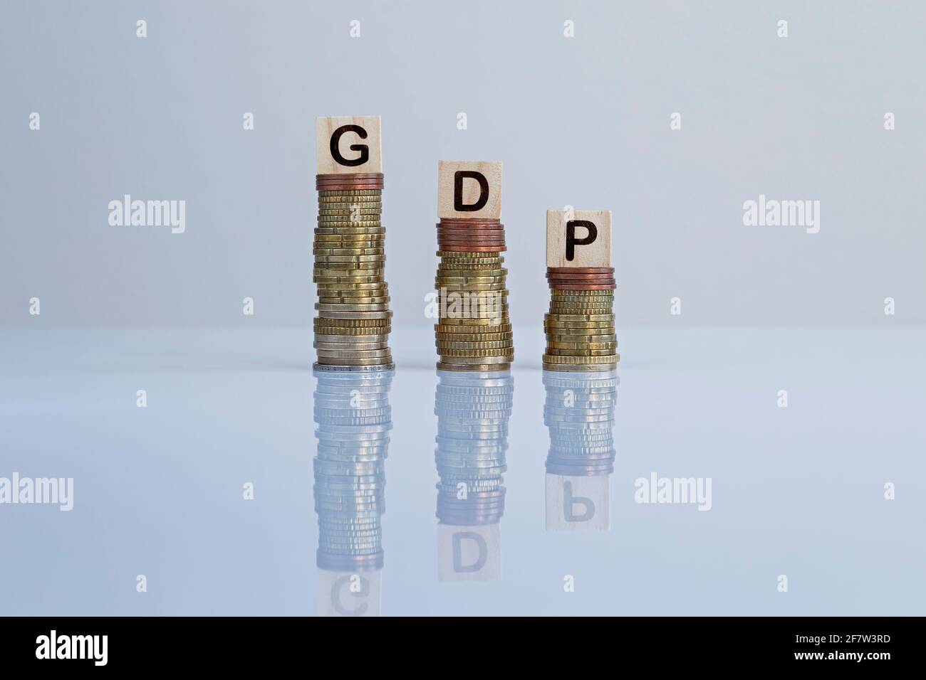 Word "GDP" on wooden blocks on top of descending stacks of coins ...