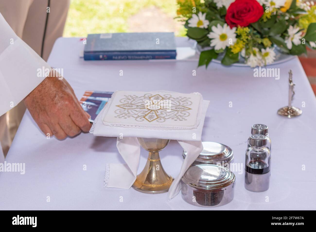 White-robed priest conducting a marriage with holy water, bible, and ...
