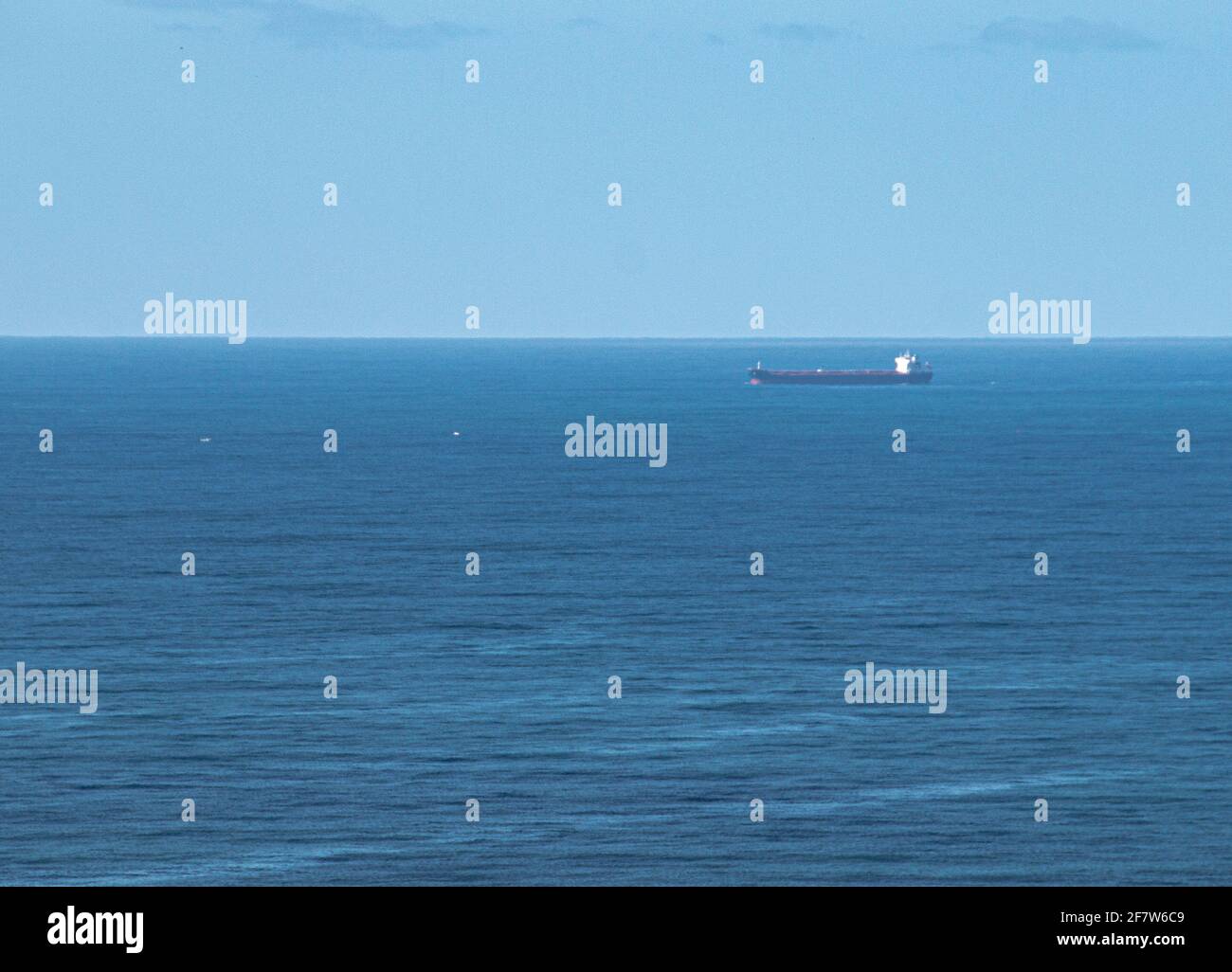 Cargo ship leaving port on calm sea Stock Photo - Alamy