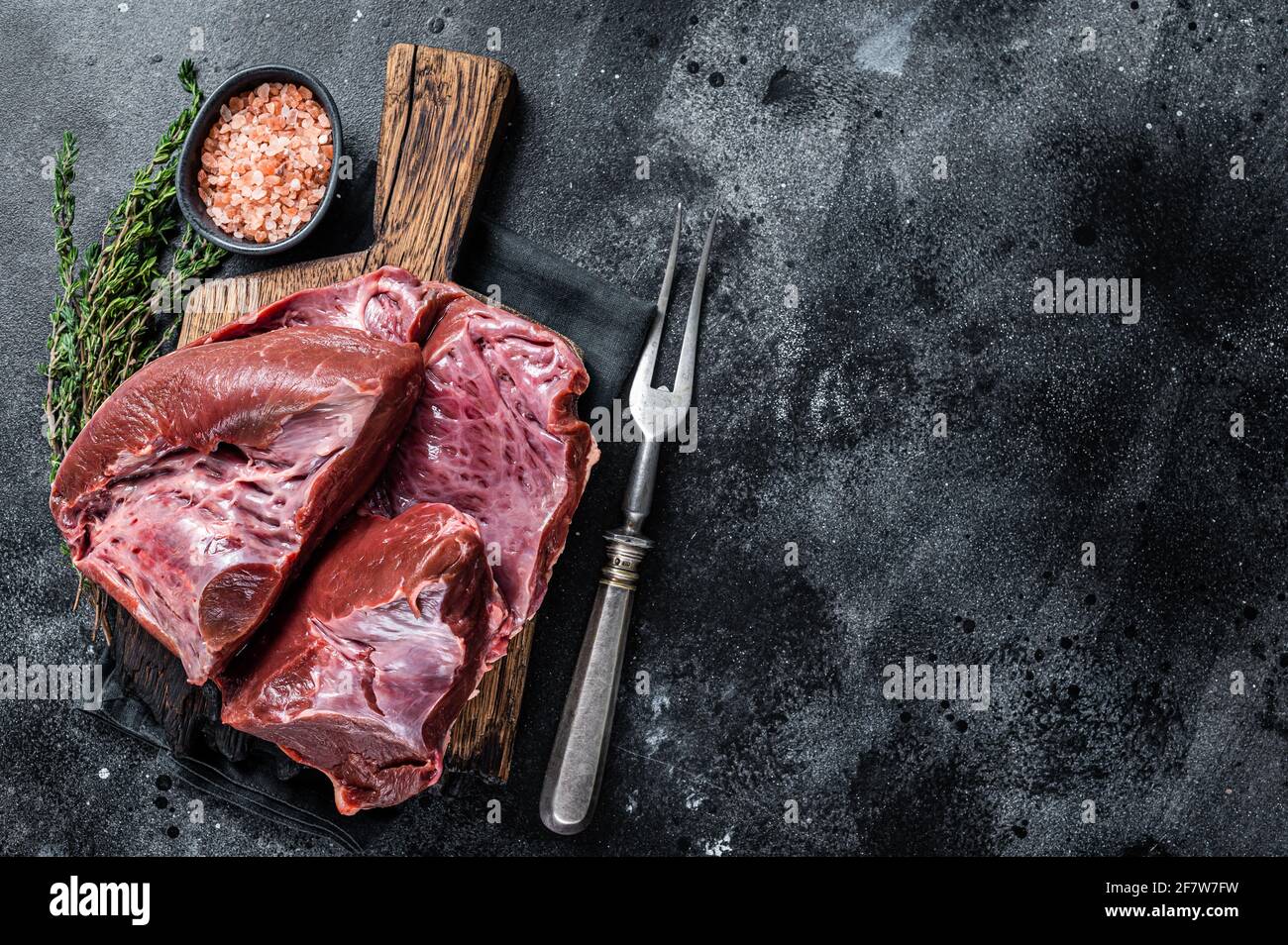 Raw cutted Beef or veal heart on a butcher board. Black background. Top ...