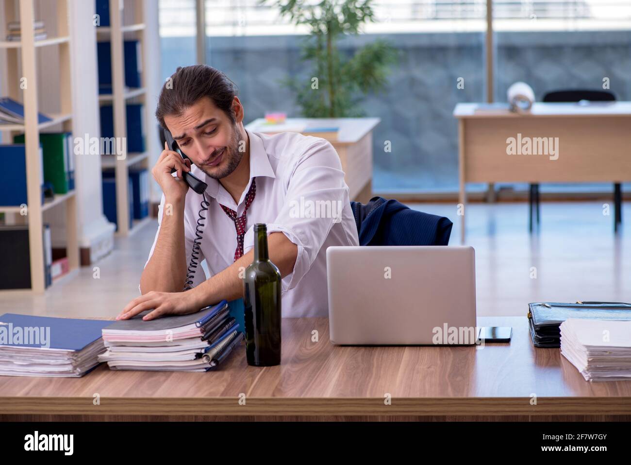 Young alcohol addicted employee working in the office Stock Photo - Alamy