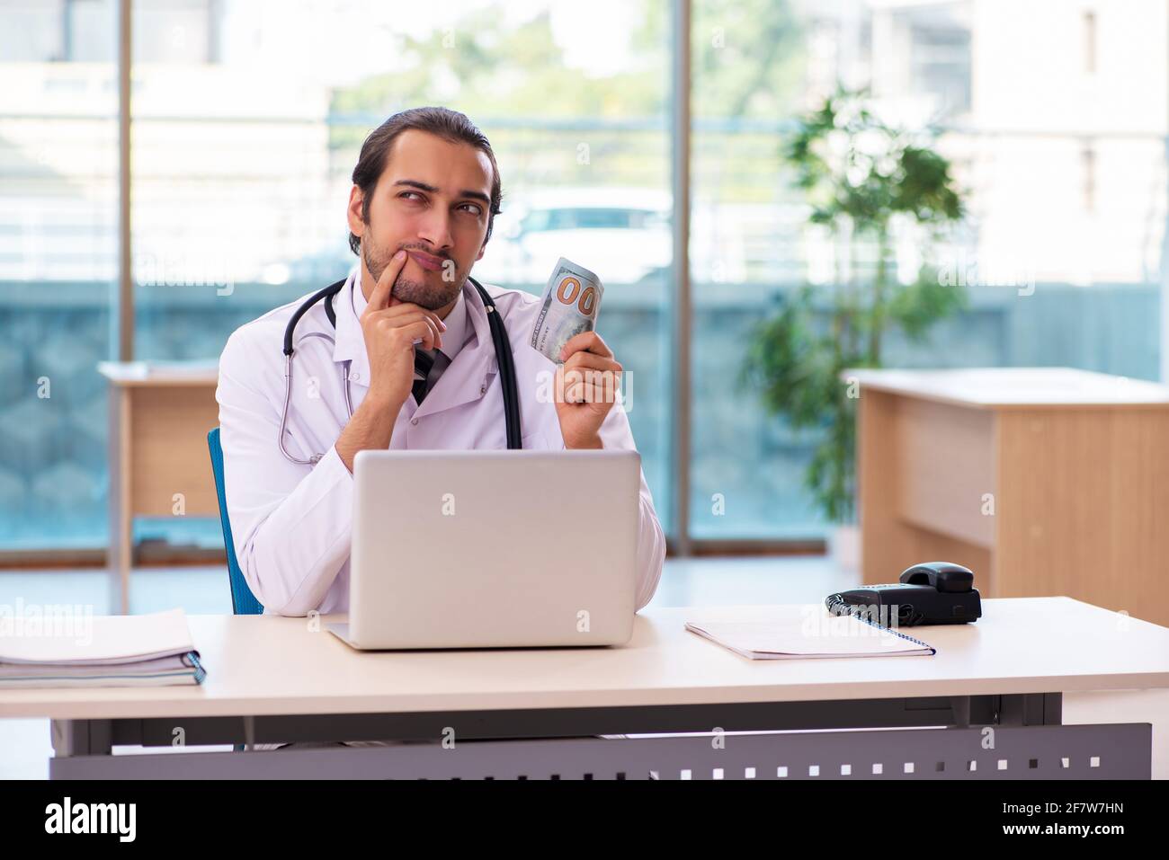 Young medic holding banknote in the clinic Stock Photo - Alamy