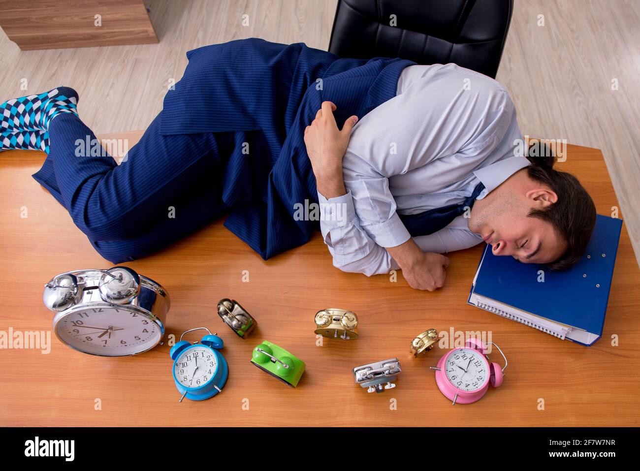 Young businessman sleeping in the office in time management concept ...