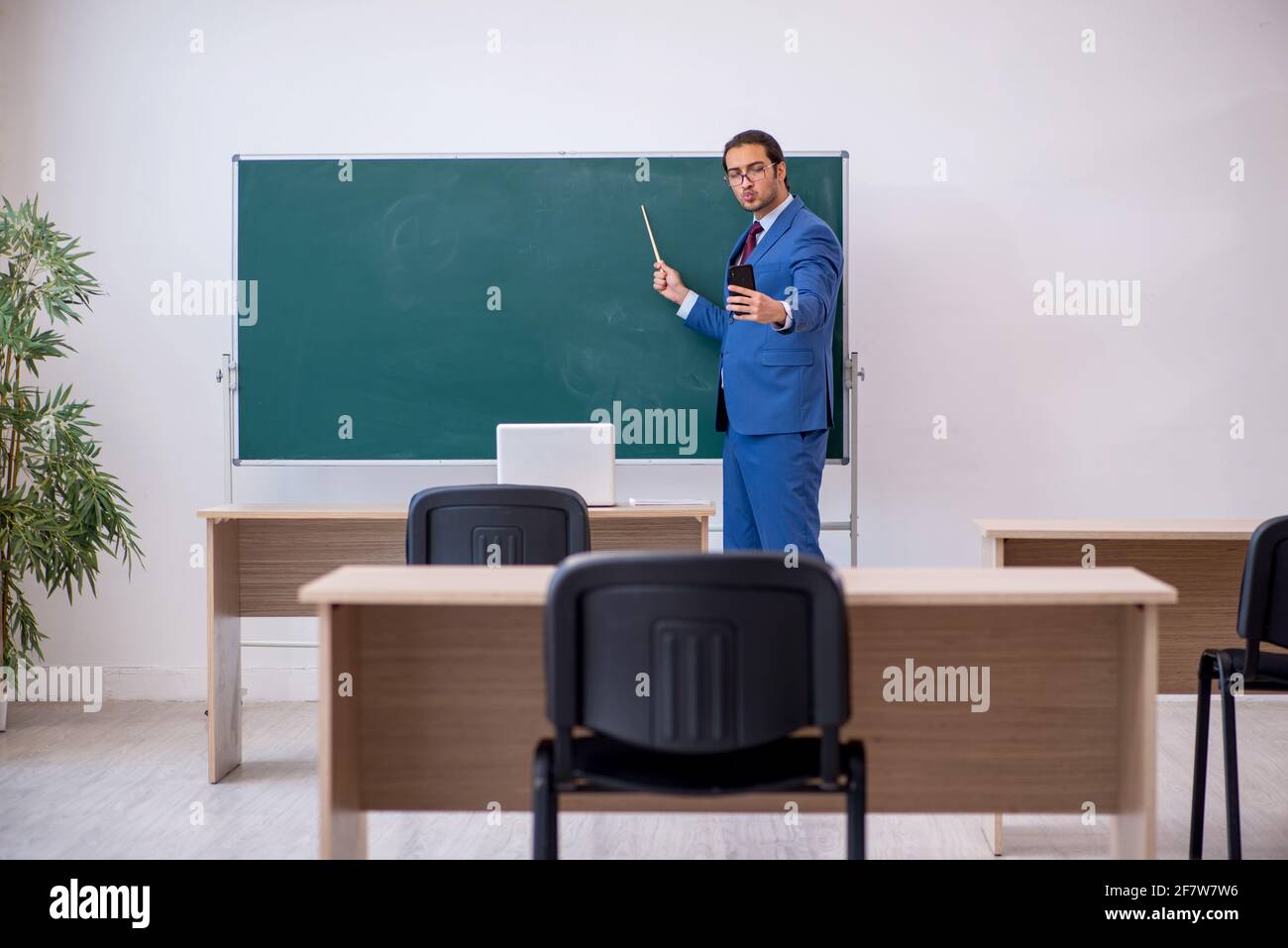 Young teacher in suit in front of green board Stock Photo - Alamy