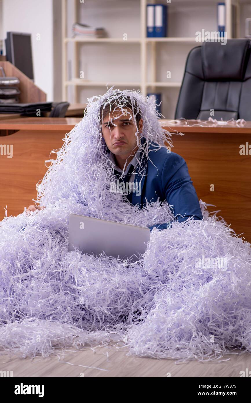 Young male employee cutting papers in the office Stock Photo - Alamy
