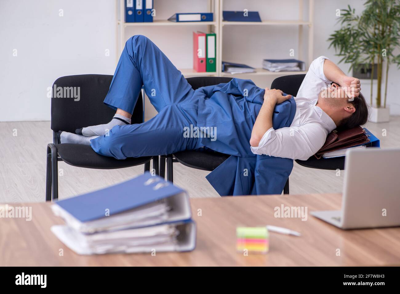 Young employee sleeping in the office on chairs Stock Photo - Alamy
