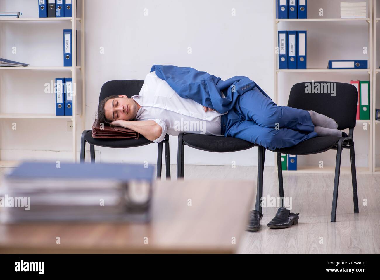 Young employee sleeping in the office on chairs Stock Photo - Alamy