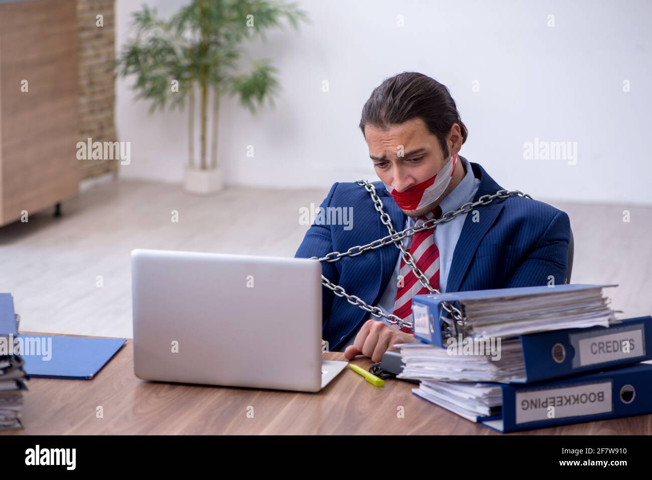 Chained employee unhappy with excessive work in the office Stock Photo ...