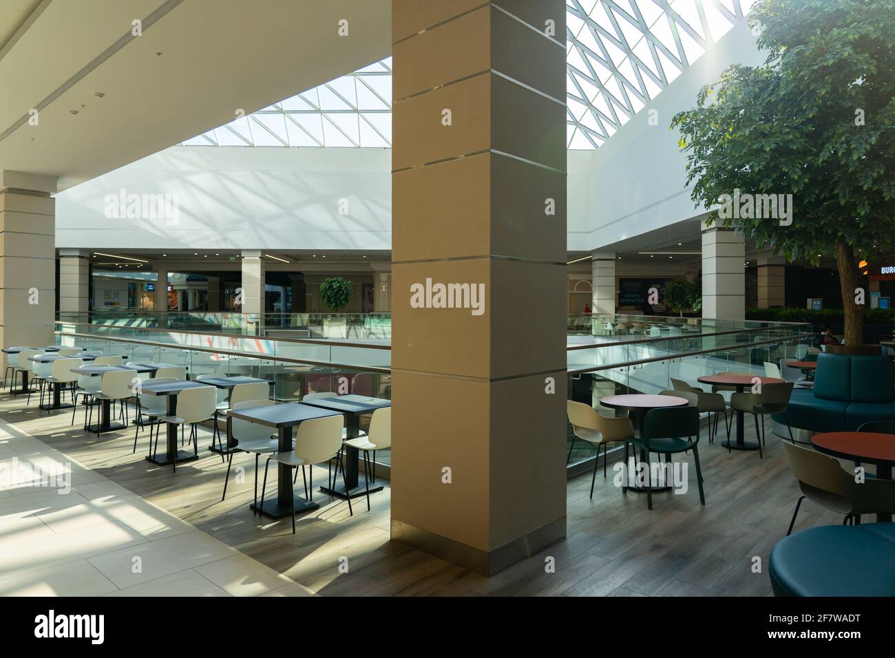A row of tables with white chairs for visitors to the food court of a ...