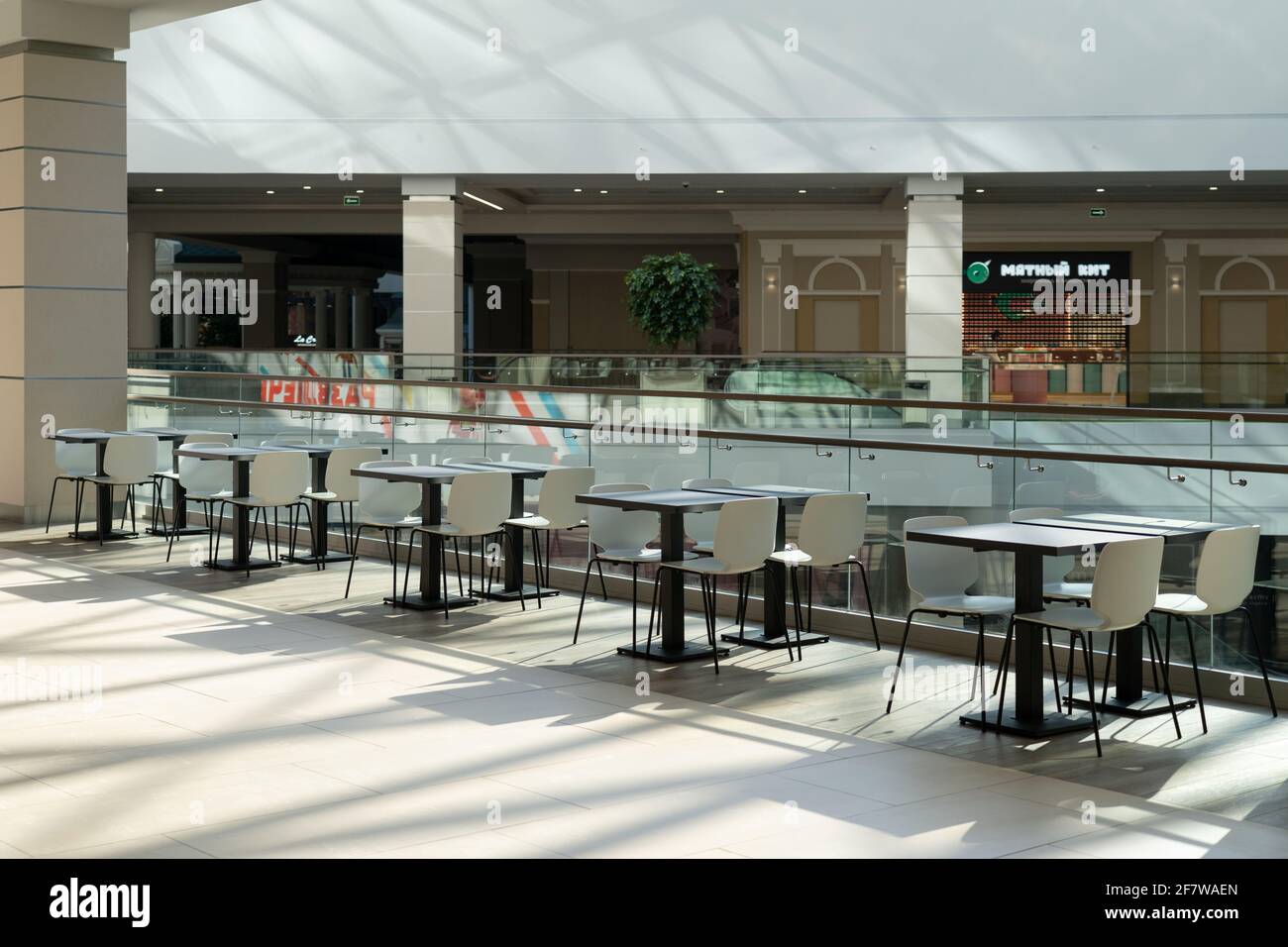 A row of tables with white chairs for visitors to the food court of a ...