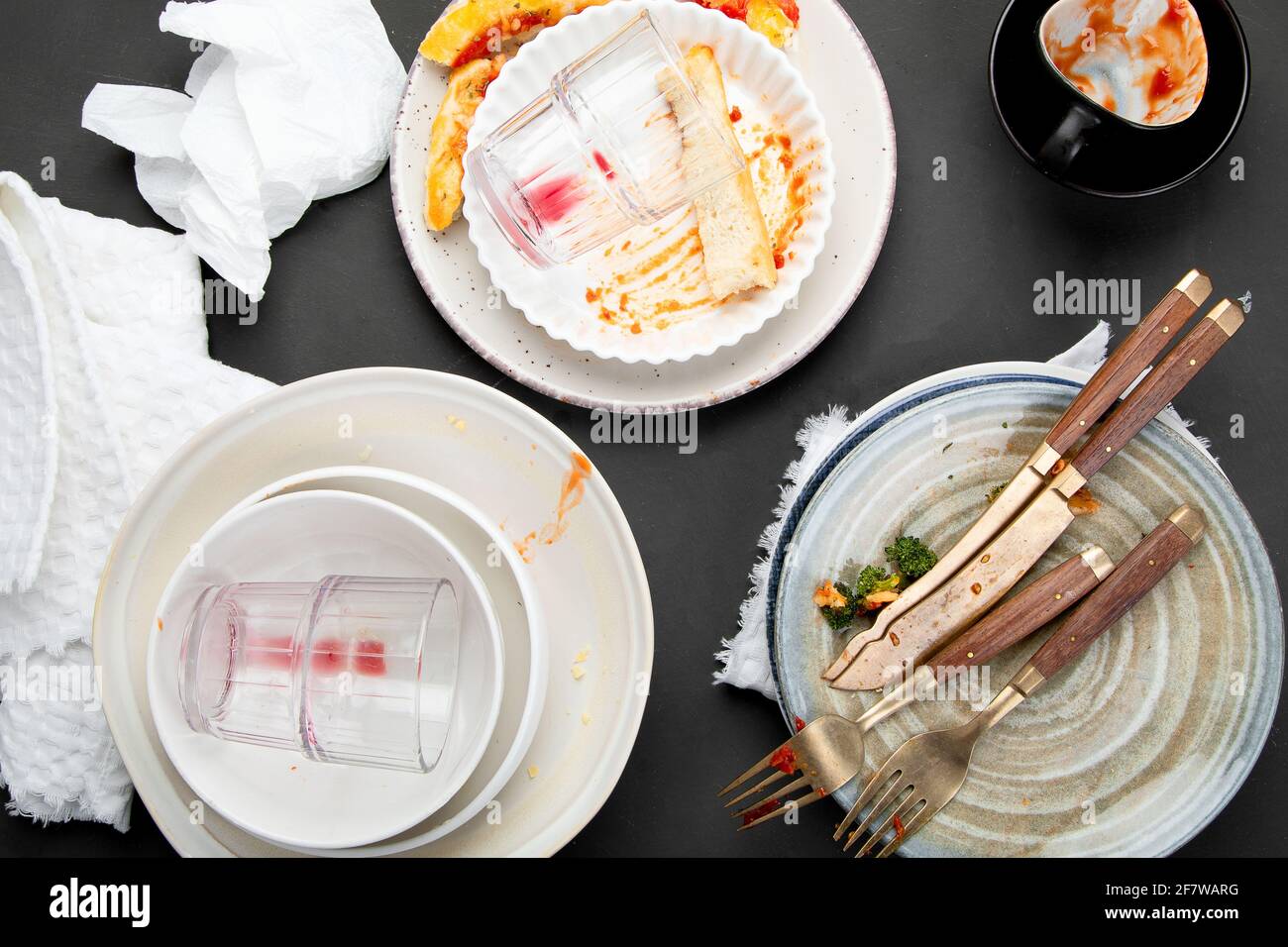 Pile of empty and dirty plates with food leftovers on dark background ...