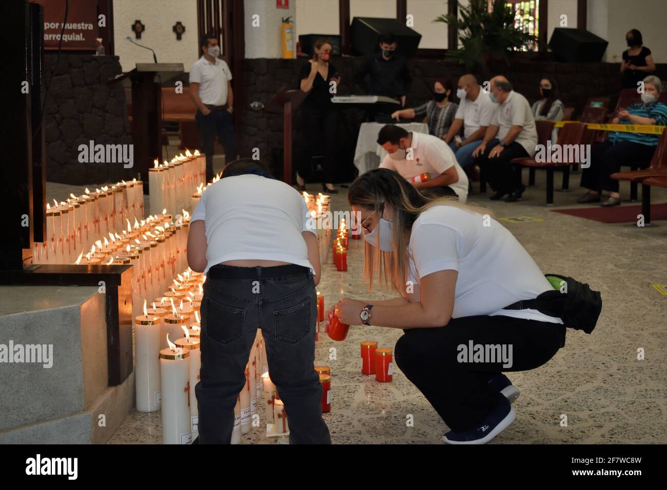 MEDELLIN, COLOMBIA - Apr 03, 2021: A woman and a child light candles ...