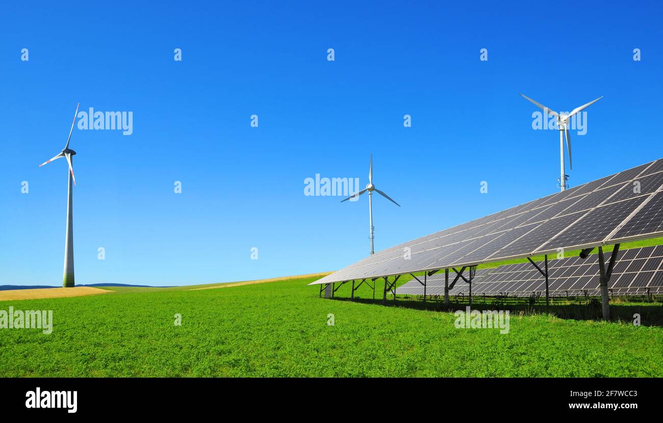 Solar panels with wind turbines on meadow. Power plant using renewable ...