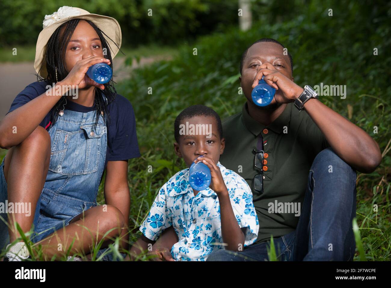 a young family sitting in a park drinking water Stock Photo - Alamy