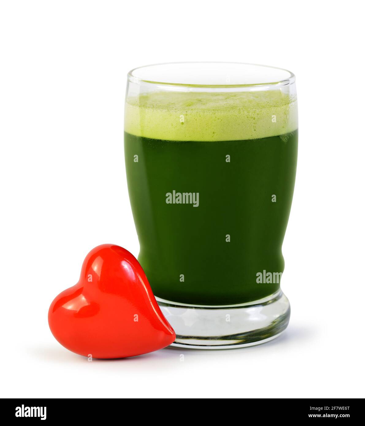 Green barley juice drink in glass and red heart isolated on white ...