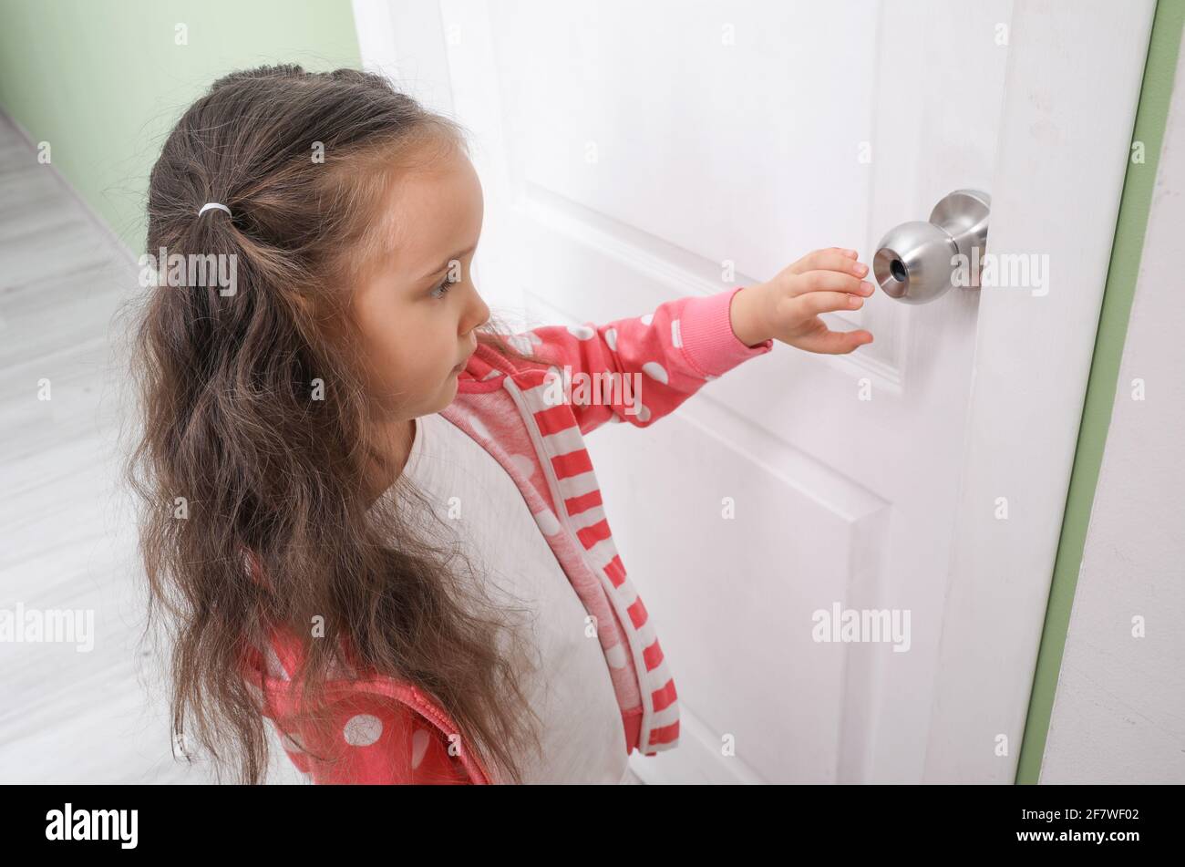 Cute little girl standing near closed door Stock Photo - Alamy