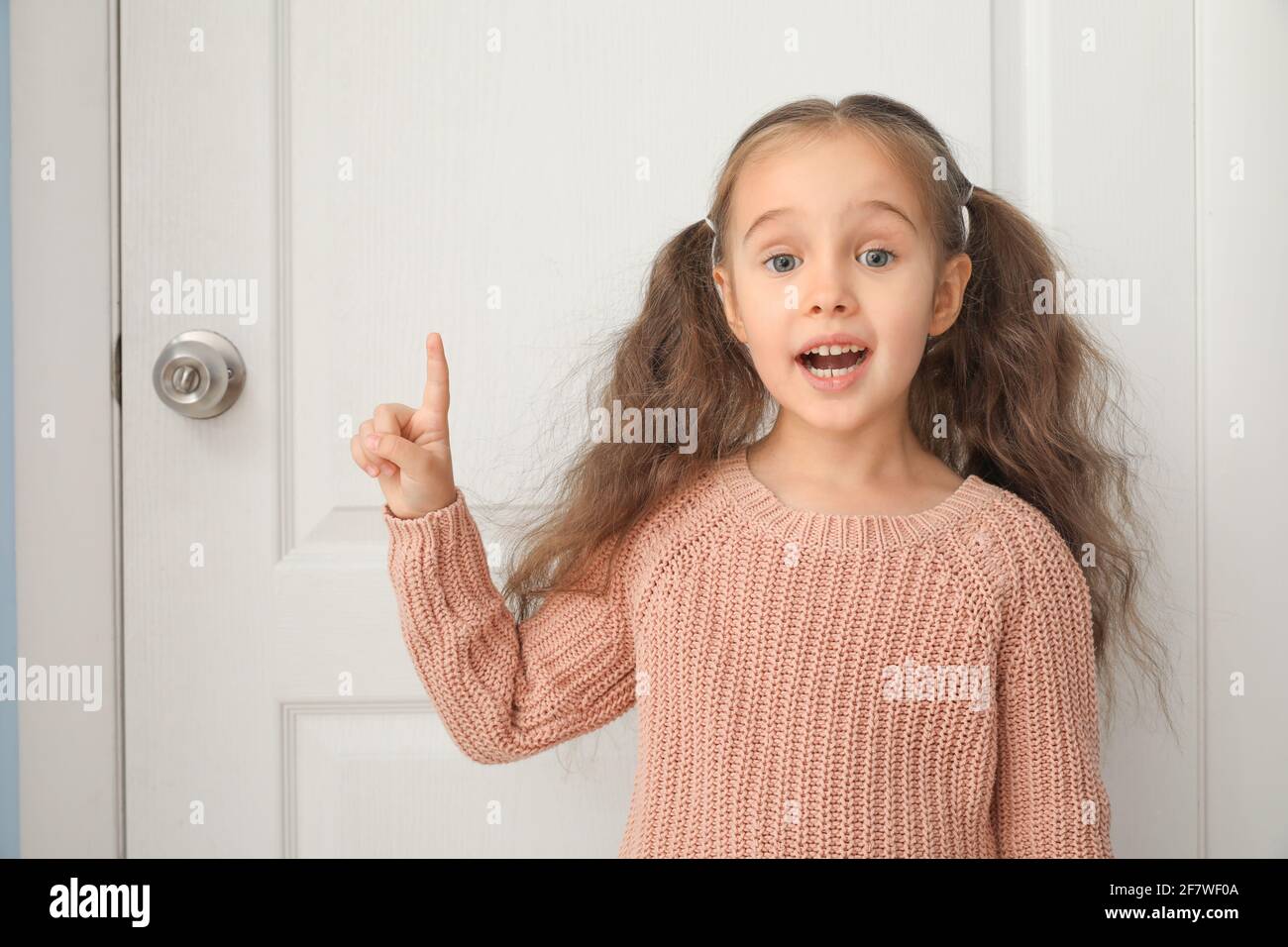 Cute little girl standing near closed door Stock Photo - Alamy