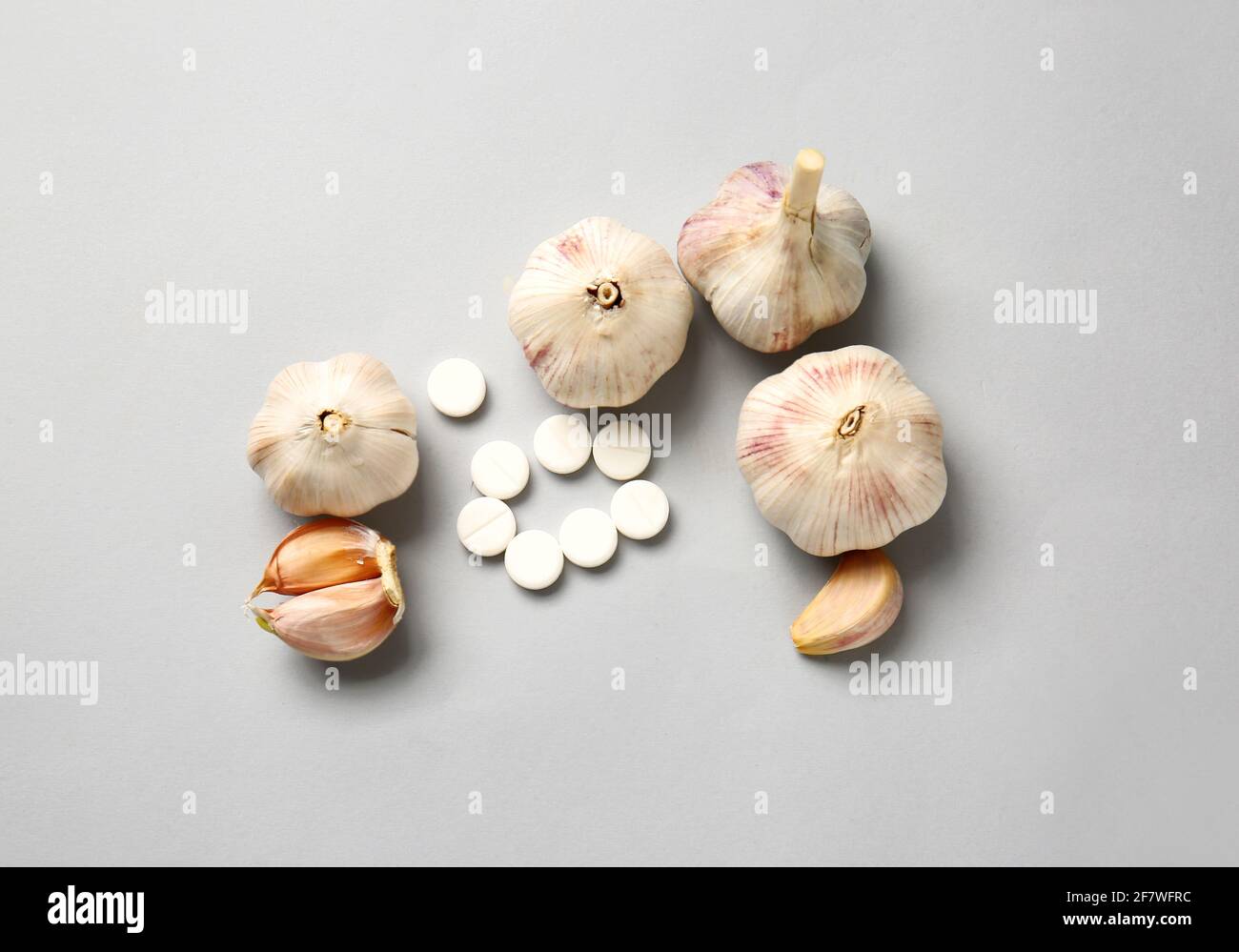 Fresh garlic with pills on light background Stock Photo - Alamy