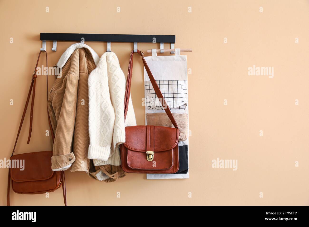 Stylish clothes hanging on wall in hall Stock Photo - Alamy