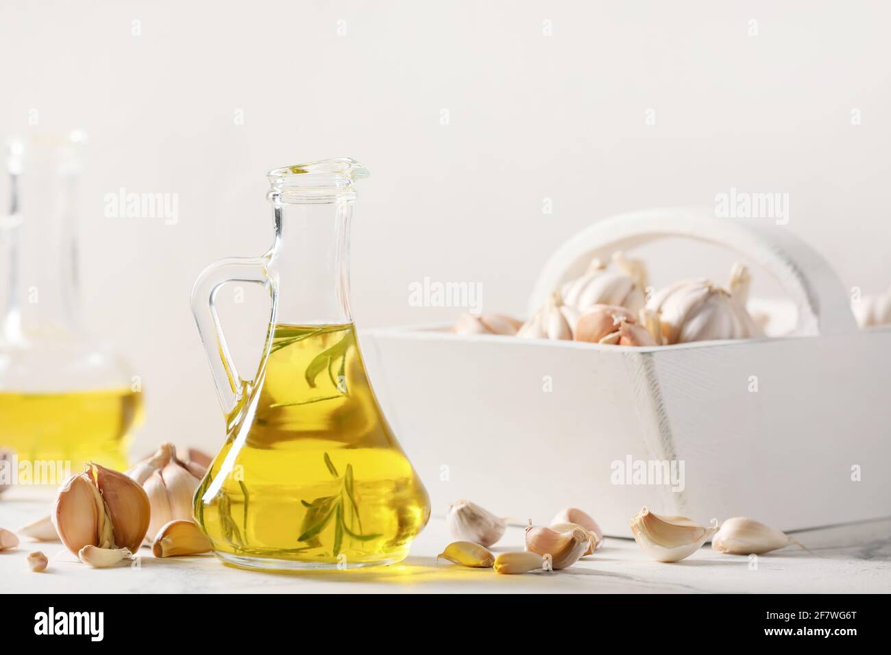Jug of garlic oil on light background Stock Photo - Alamy