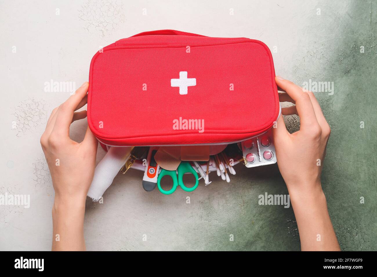 Female hands with first aid kit on light background Stock Photo - Alamy