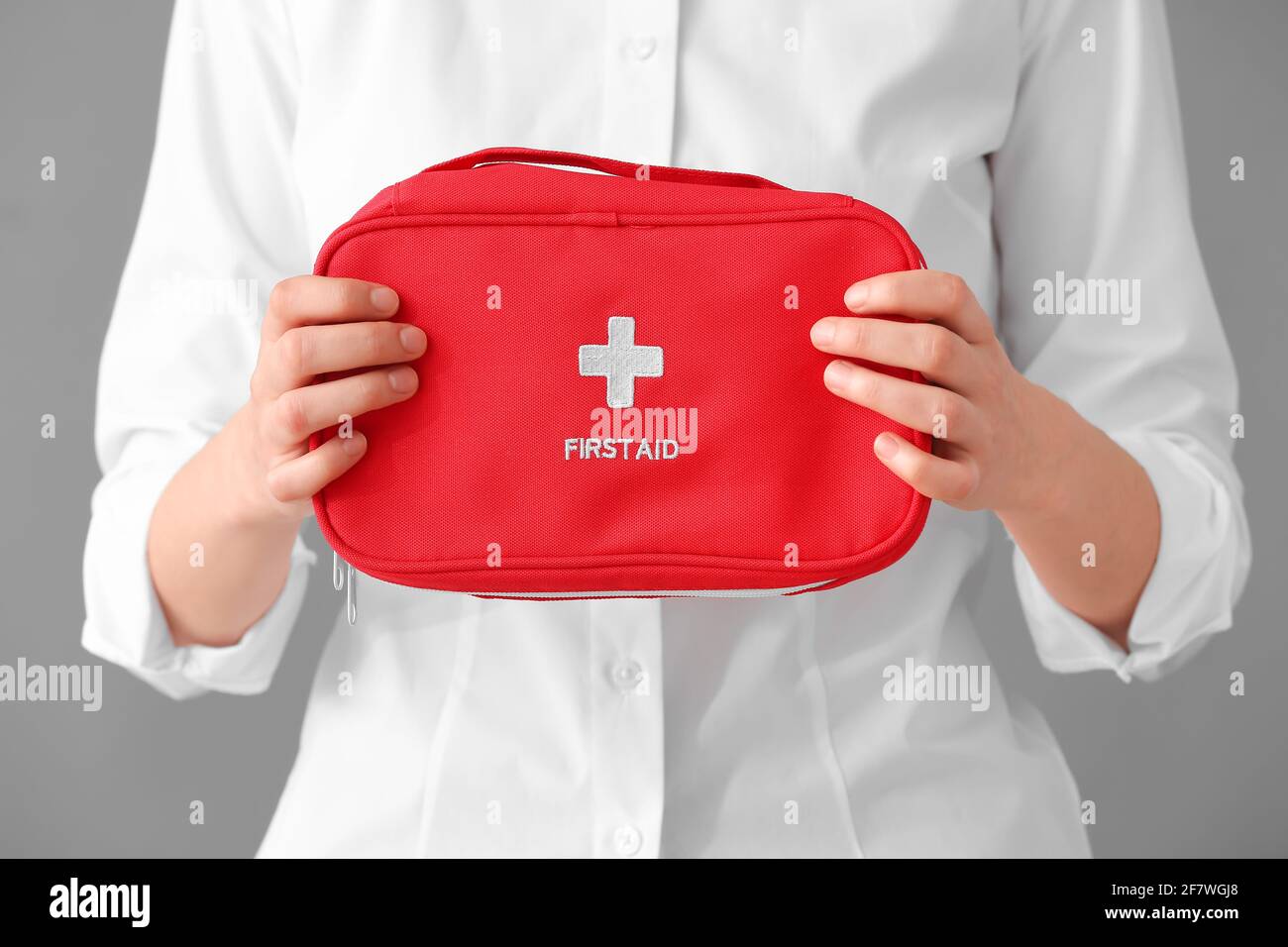 Woman with first aid kit on grey background, closeup Stock Photo - Alamy
