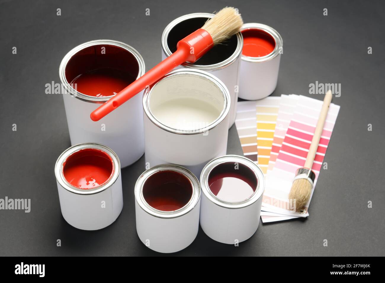 Cans of paints with palette samples and brushes on dark background ...