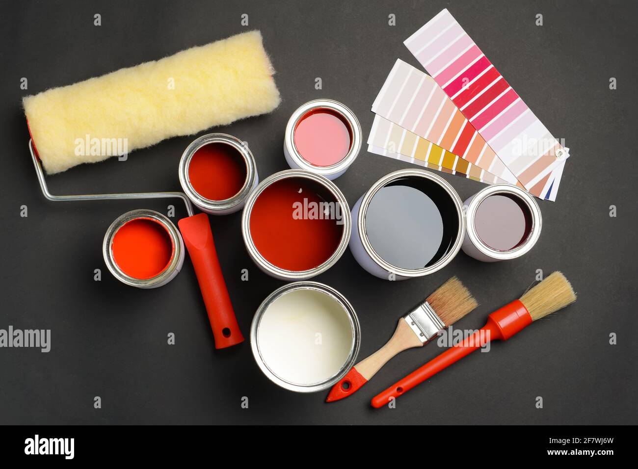 Cans of paints, palette samples, roller and brushes on dark background ...