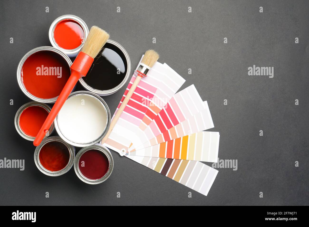 Cans of paints with palette samples and brushes on dark background ...