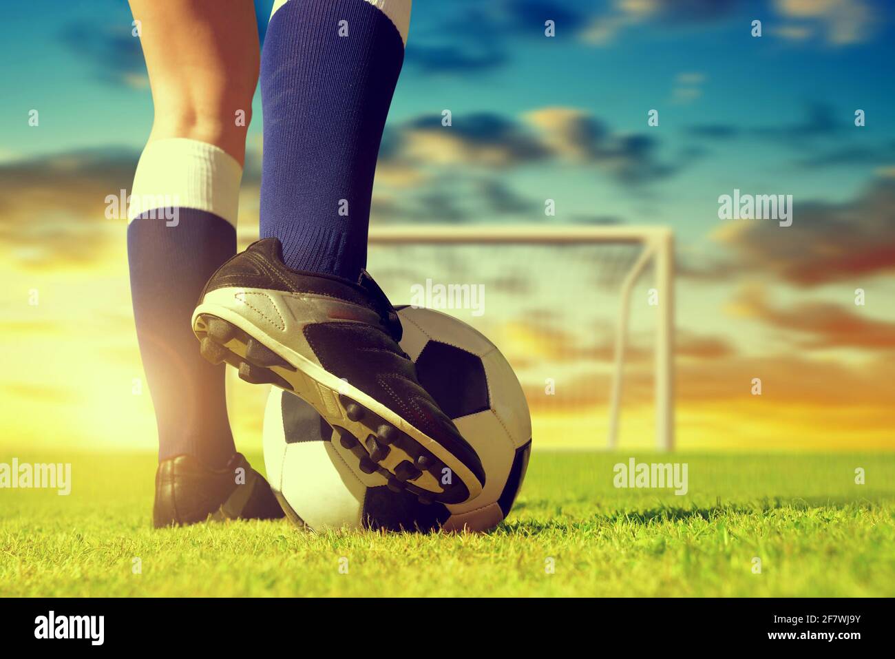Soccer ball with feet player on the football field at sunset Stock ...