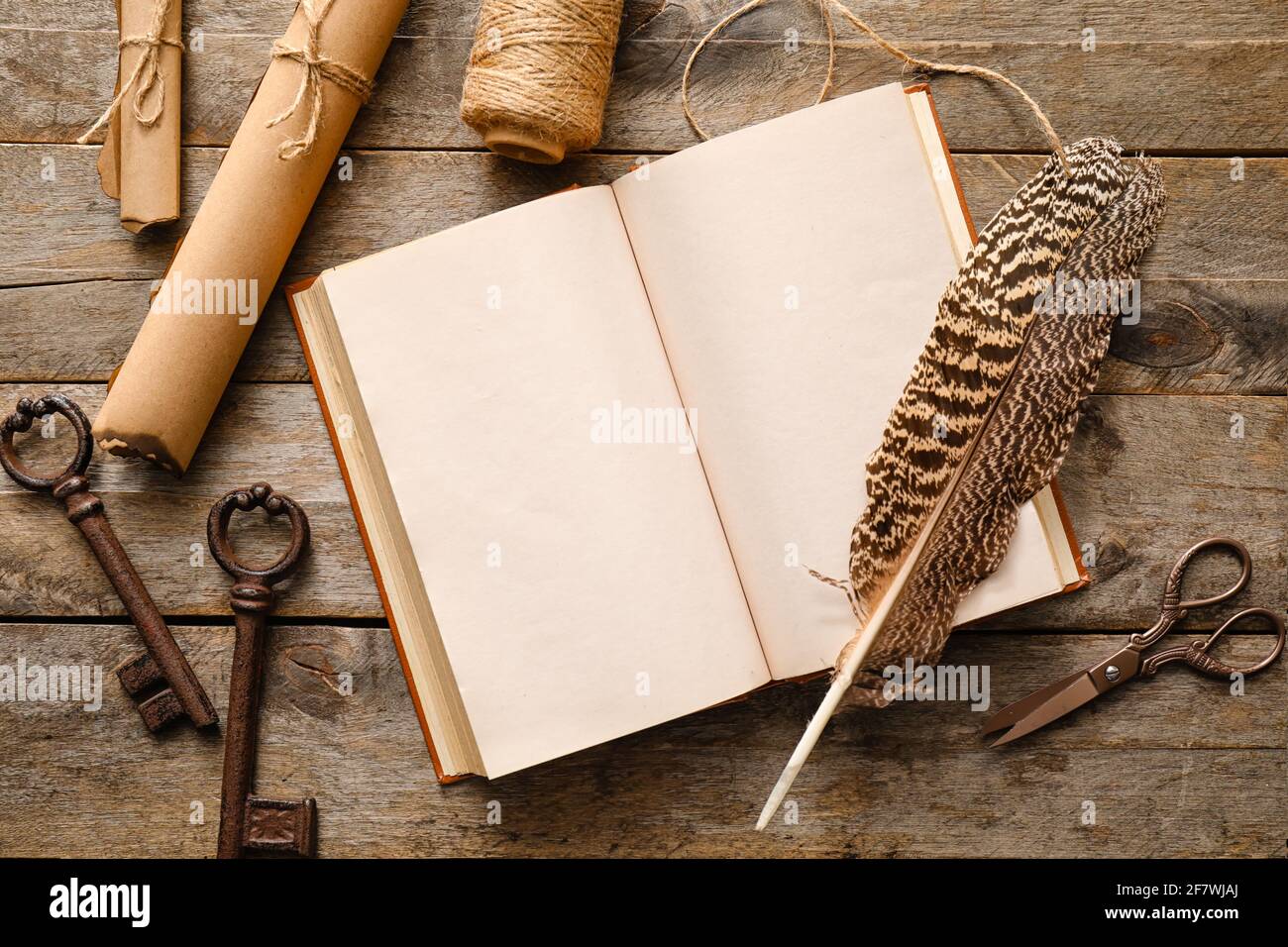 Open old book with scrolls, feather and keys on wooden background Stock ...