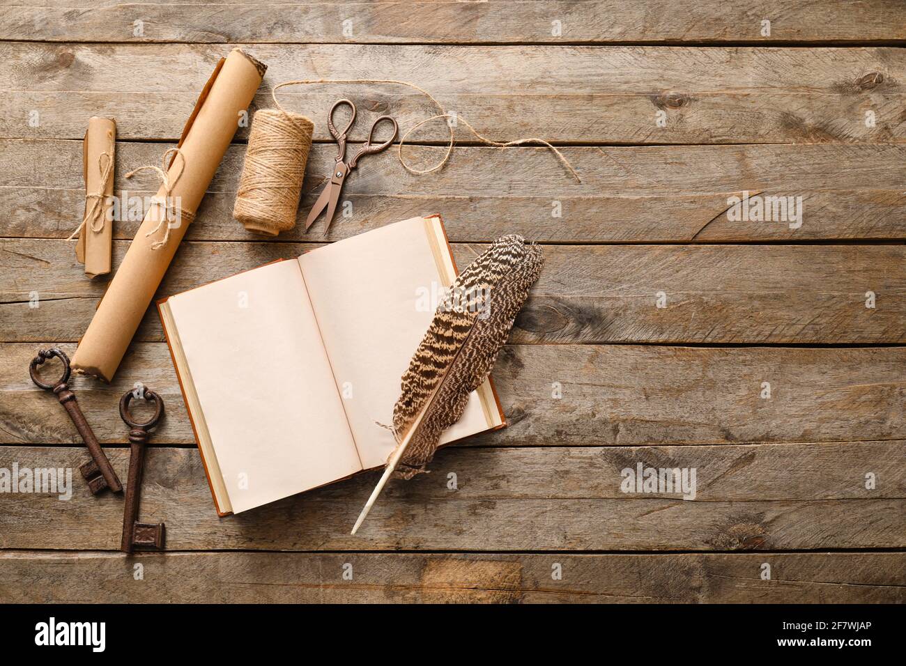 Open old book with scrolls, feather and keys on wooden background Stock ...