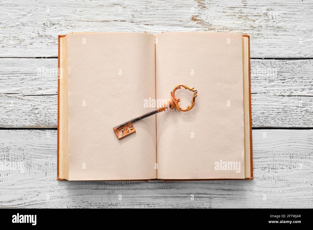 Open old book with key on light wooden background Stock Photo - Alamy