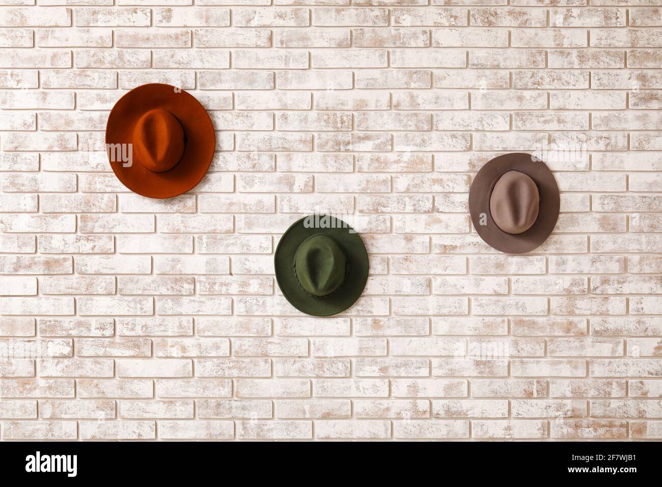 Stylish hats on light brick background Stock Photo - Alamy