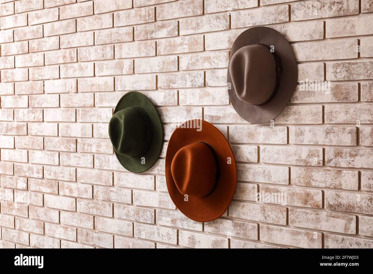 Stylish hats on light brick background Stock Photo - Alamy