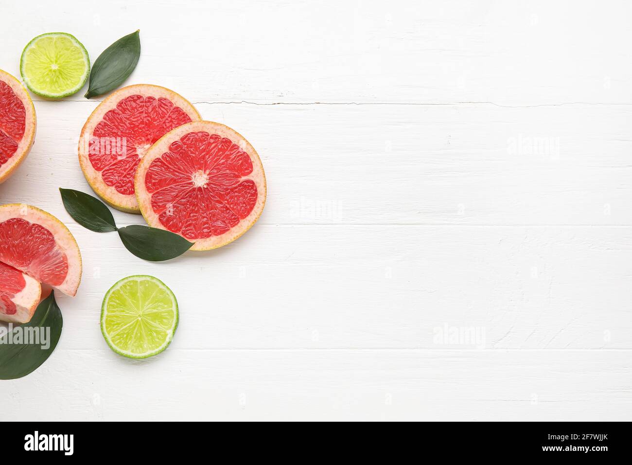 Fresh cut citrus fruits on white wooden background Stock Photo - Alamy