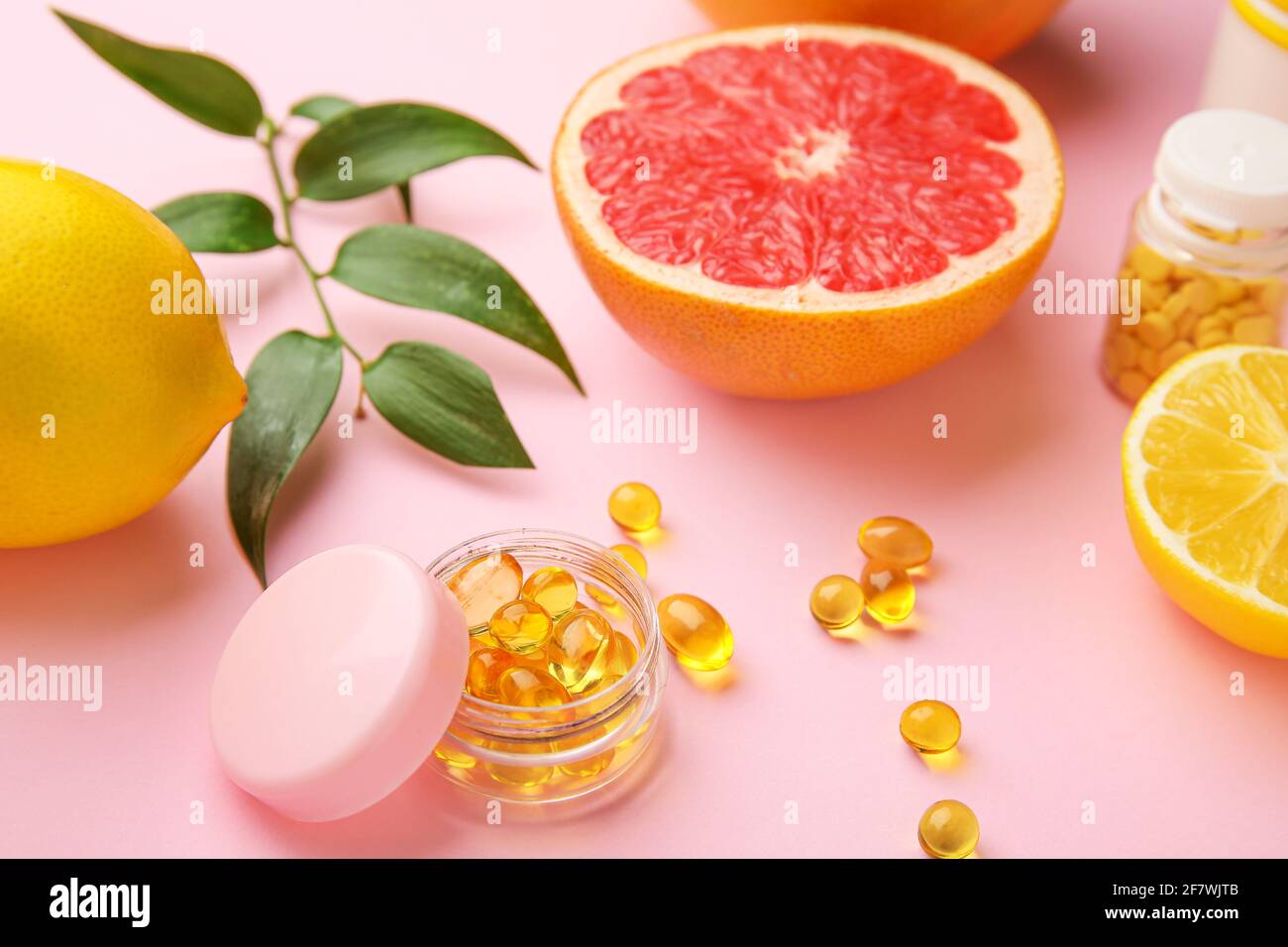 Bottles with vitamin C pills and citrus fruits on color background ...