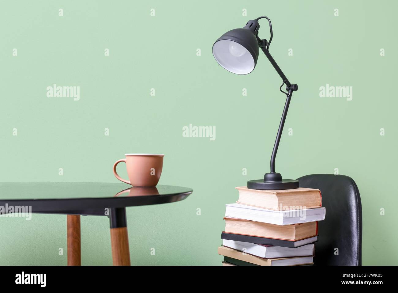 Chair with books and lamp near light wall Stock Photo - Alamy