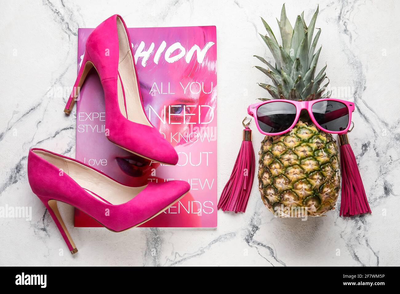 Pineapple with female accessories and fashion magazine on white ...