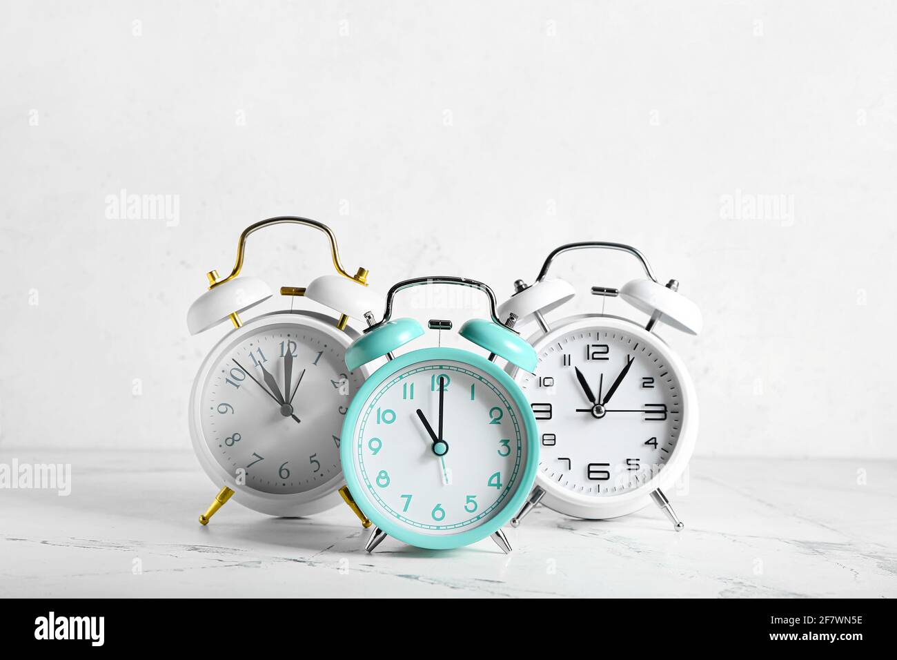 Different alarm clocks on light background Stock Photo - Alamy
