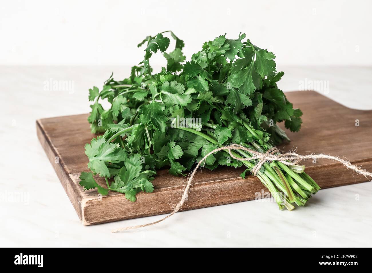 Board with fresh cilantro on white background Stock Photo - Alamy