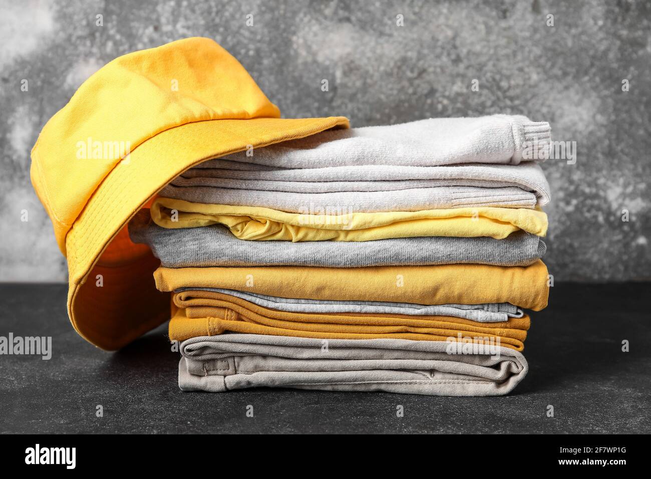 Stack of stylish clothes with hat on grunge background Stock Photo - Alamy