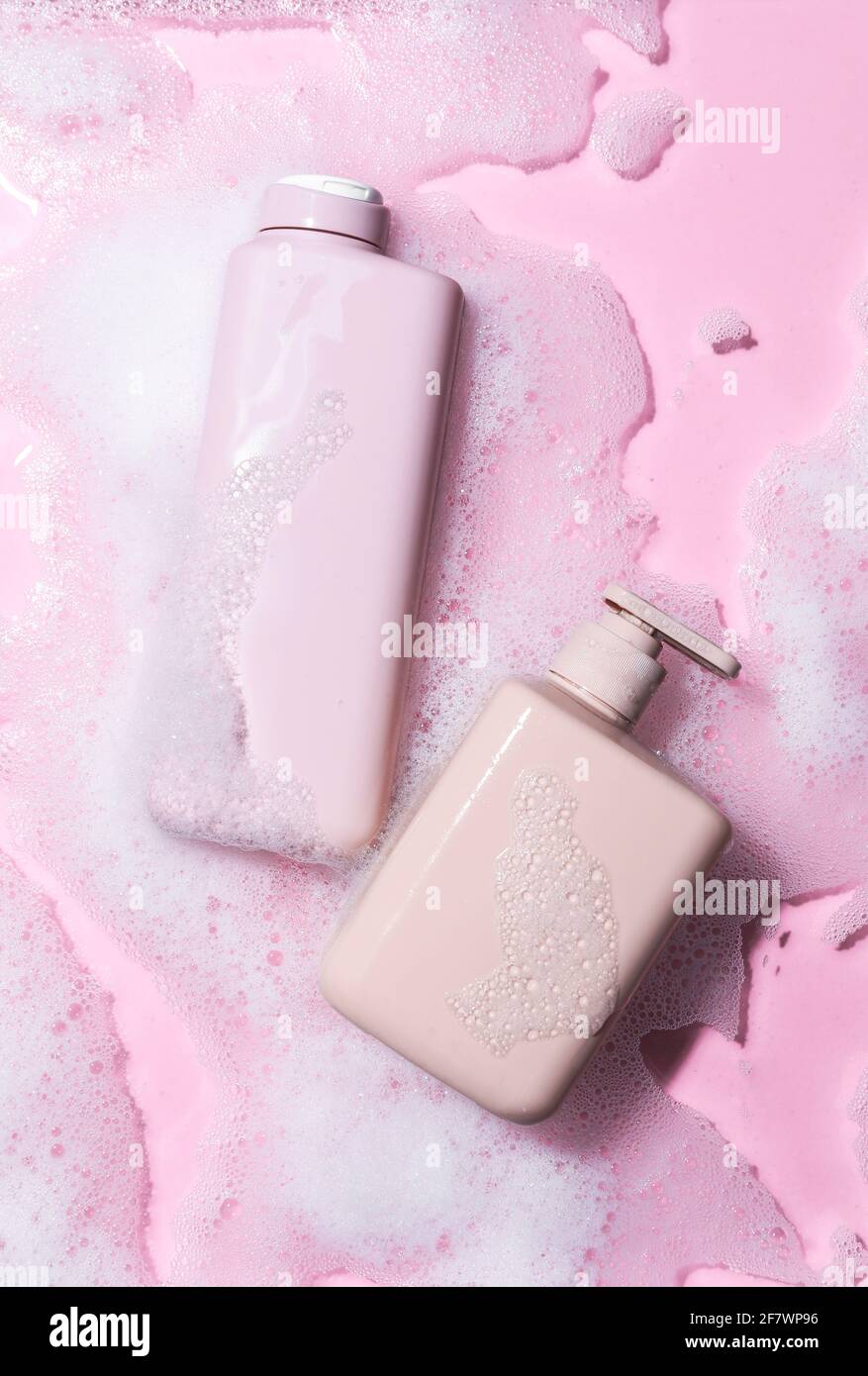 Bottles of shower gel into water with foam on color background Stock ...