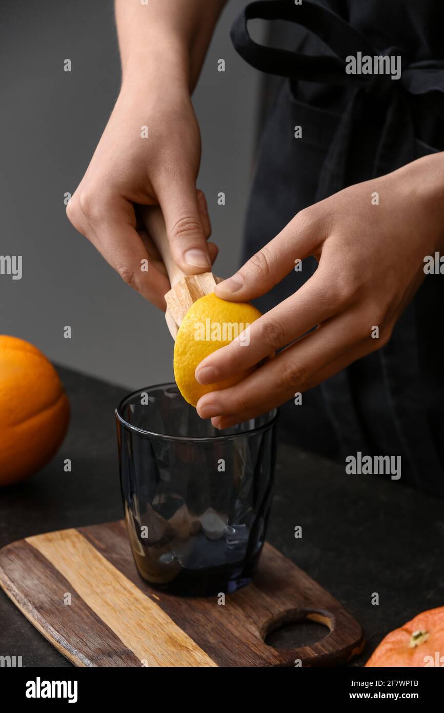 Woman squeezing lemon on dark background Stock Photo - Alamy