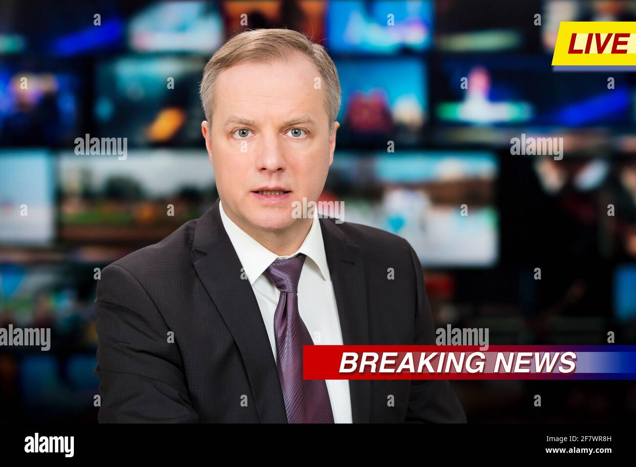 An anchorman reporting live breaking news sitting in Tv studio ...