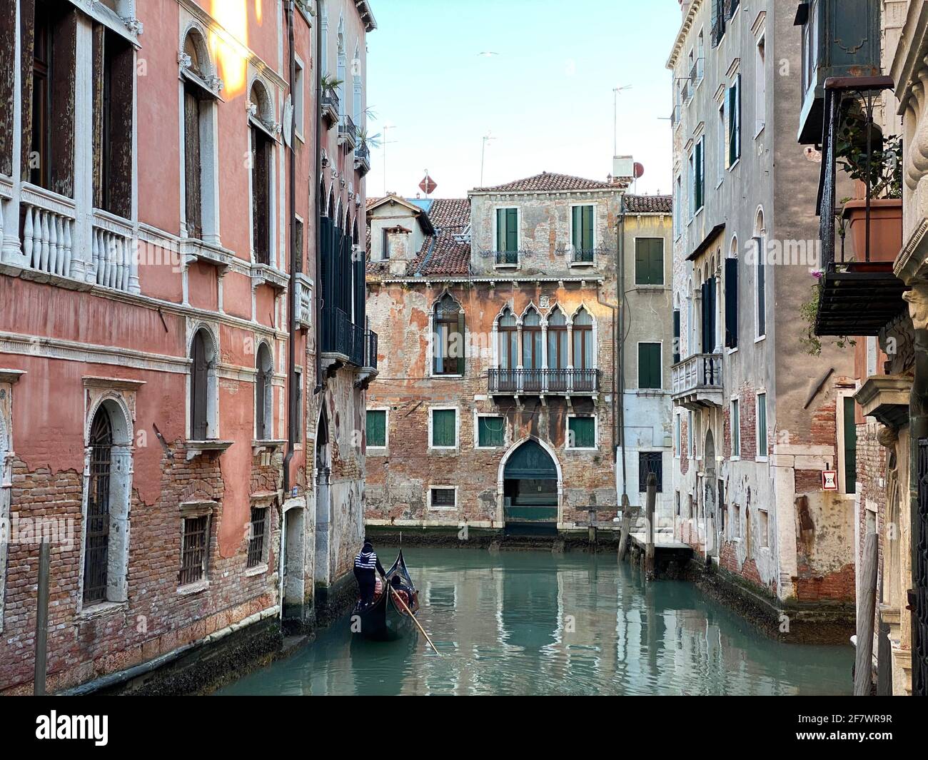 Tourist visiting Venice on a gondola on a small canal street in Venice ...